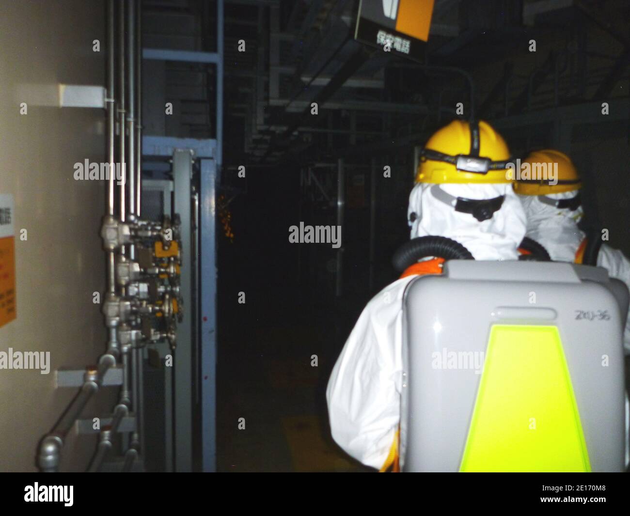 Workers wearing protective suits enter the Tokyo Electric Power Co ...