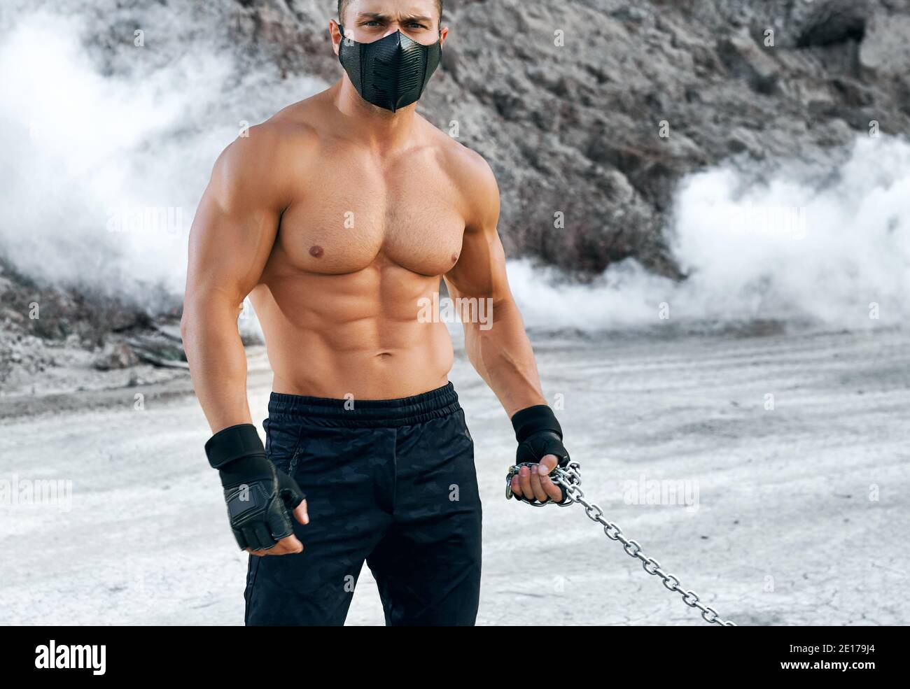 Professional bodybuilder in black protective mask standing outdoors and ...