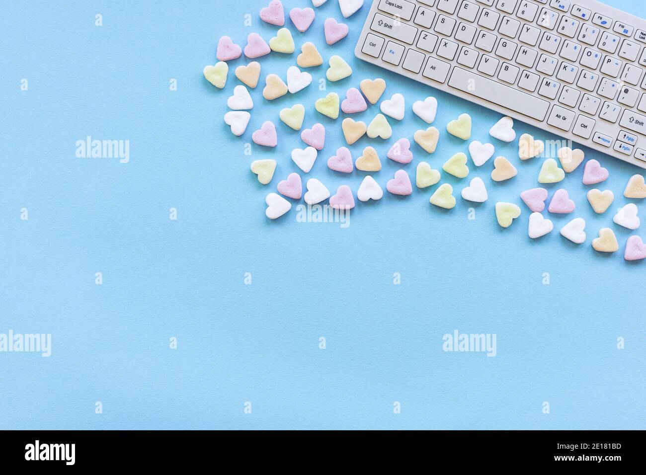 Heart shaped candies and keyboard computer on a blue table. Valentine's ...