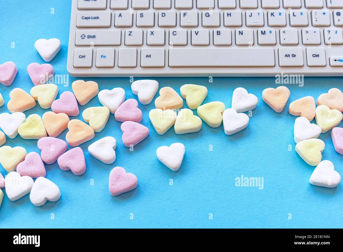 Heart shaped candies and keyboard computer on a blue table. Valentine's ...