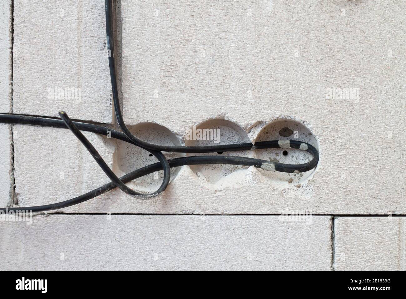 Holes in a wall made of concrete blocks with wires for power sockets ...