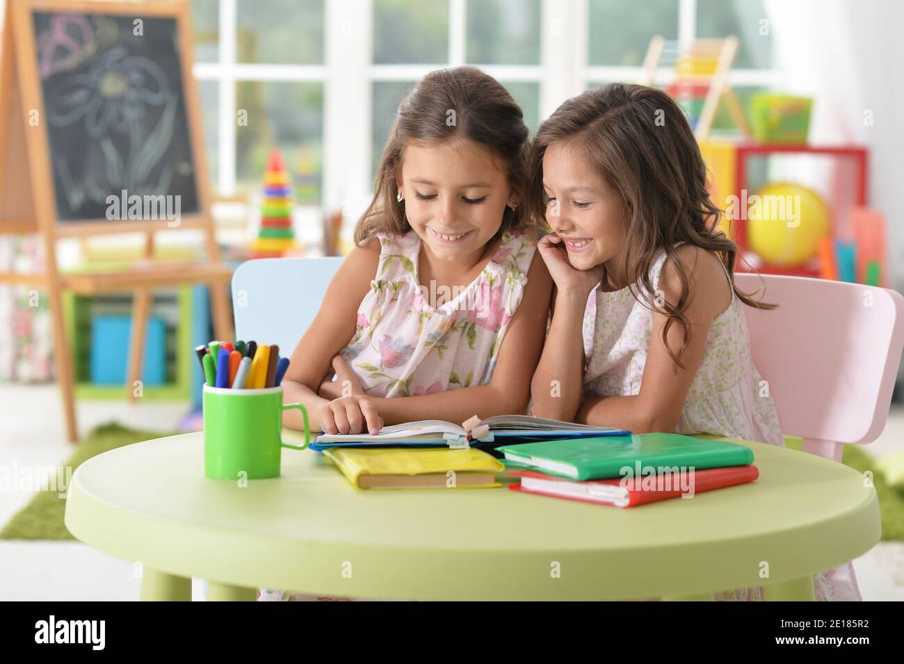 Two cute little girls drawing with pencils Stock Photo - Alamy