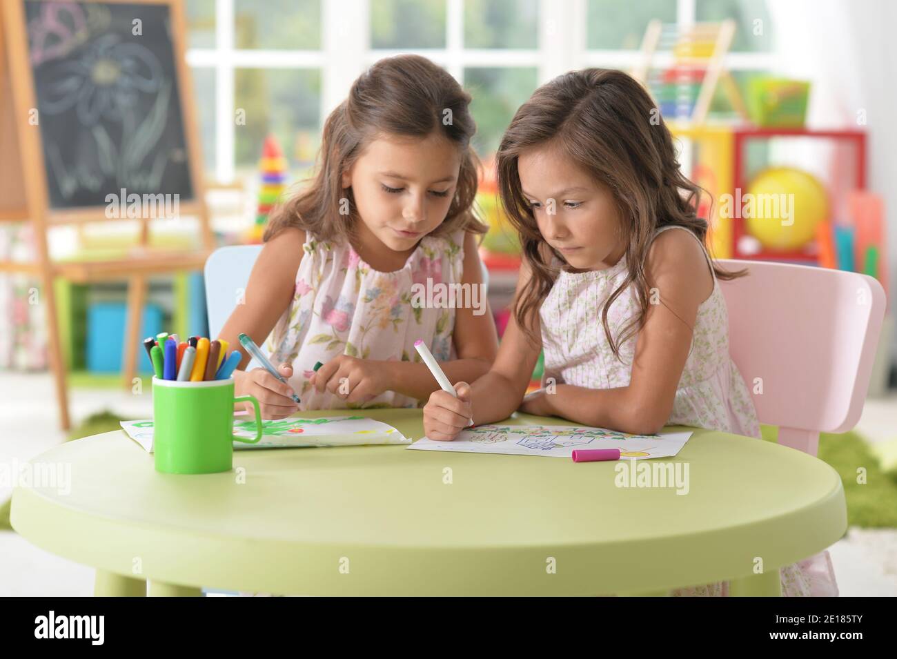 Two cute little girls drawing with pencils Stock Photo - Alamy