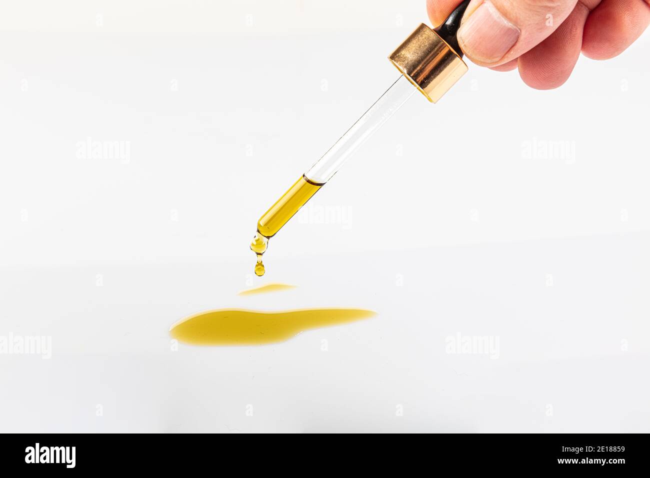 Pipette dropping black seed oil onto white background. Organic nigella ...