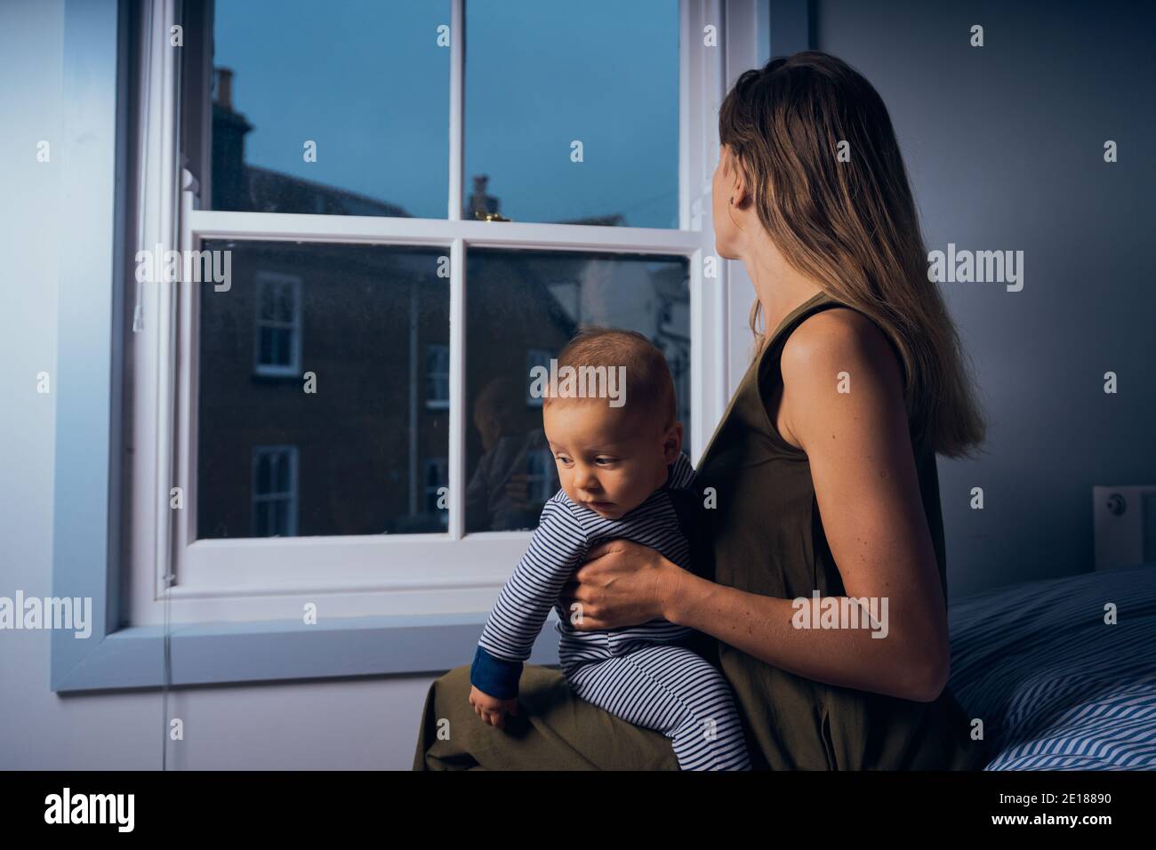 A young mother is sitting by the window with her baby Stock Photo - Alamy