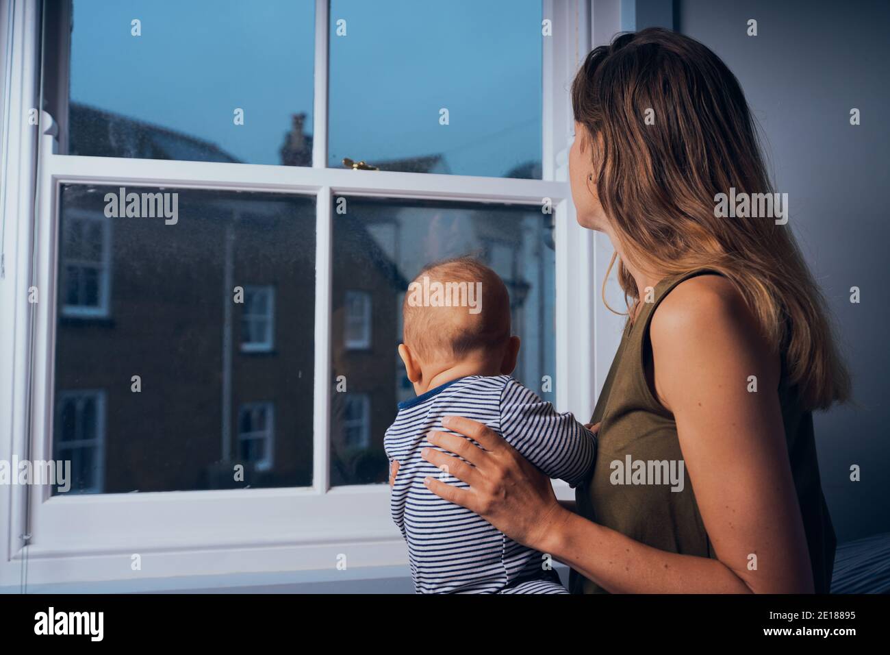 A young mother is sitting by the window with her baby Stock Photo - Alamy
