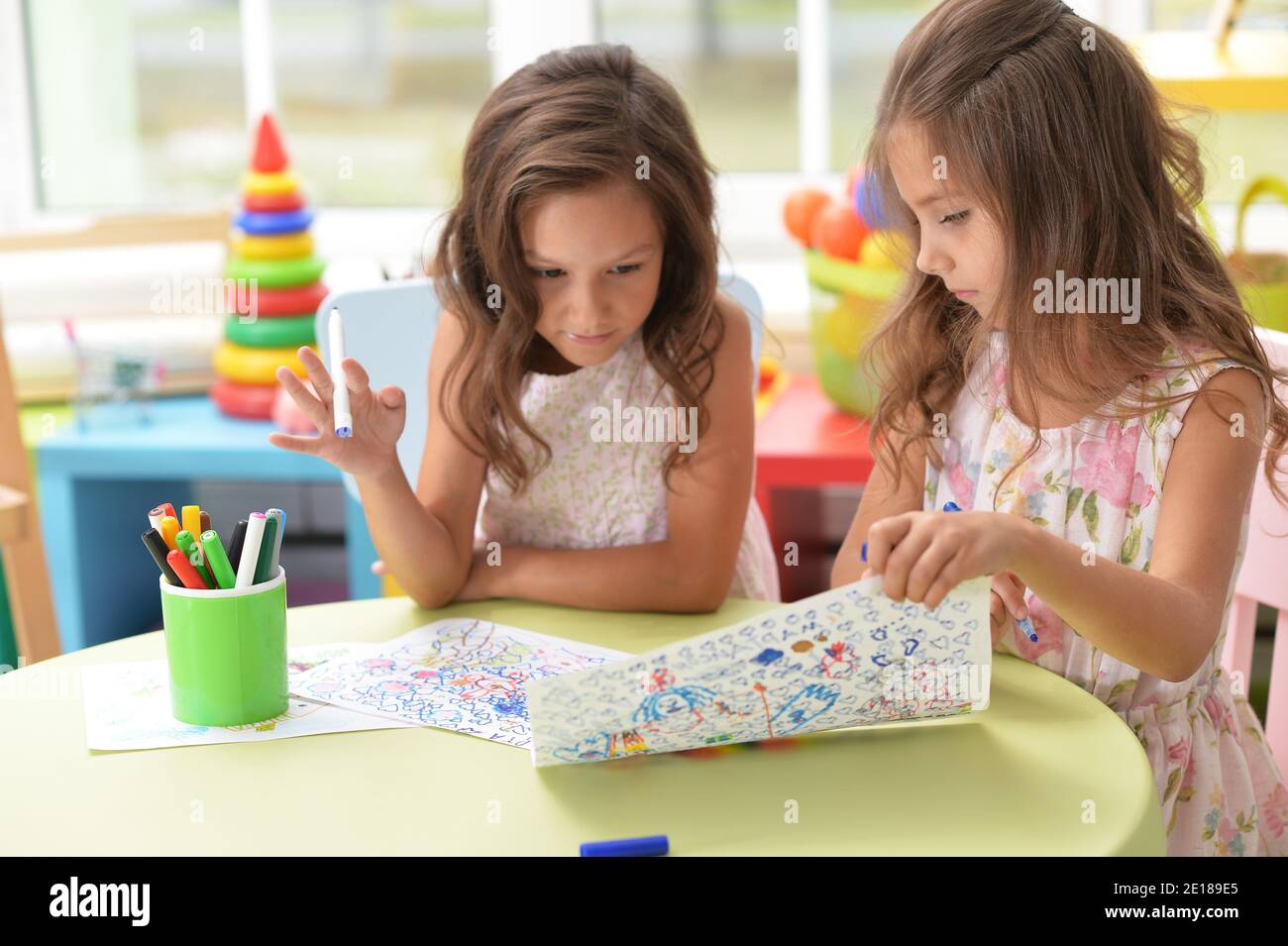 Two cute little girls drawing with pencils Stock Photo - Alamy