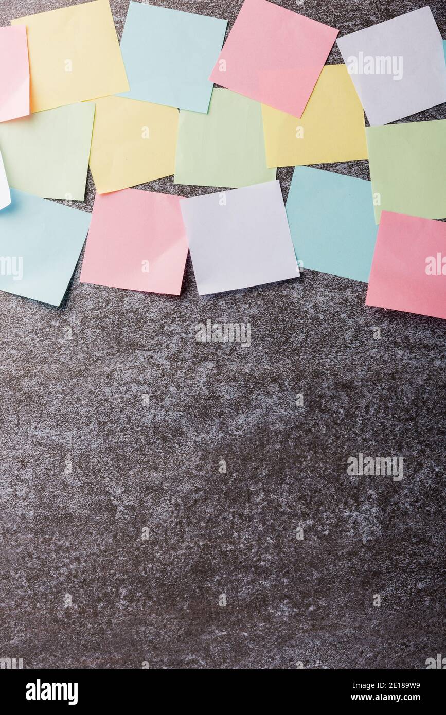 Many blank multicolored paper stick note list on concrete wall ...