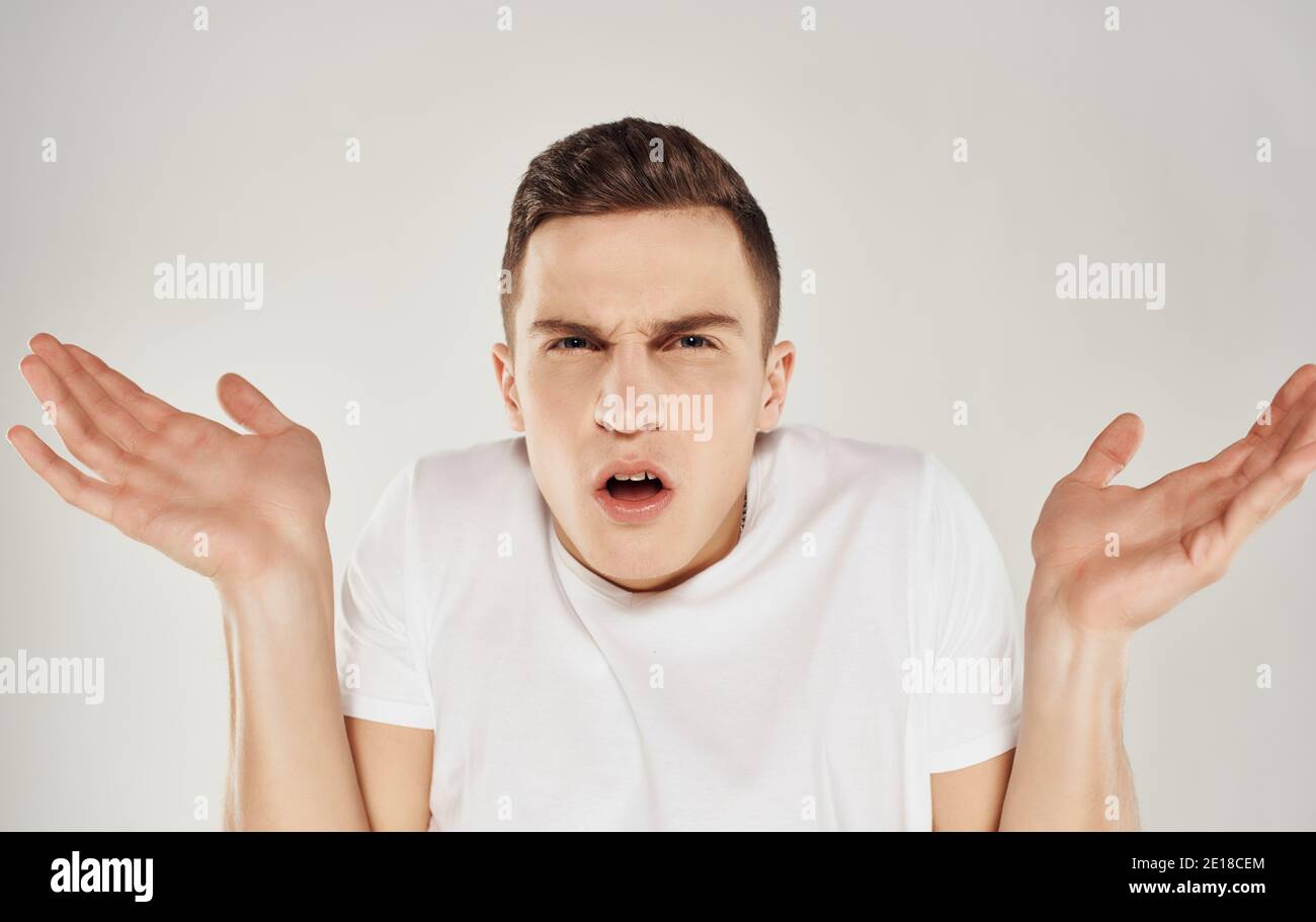 A man in a white t-shirt emotions gestures with his hands discontent ...