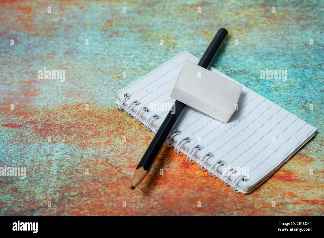 Notebook, black graphite pencil and eraser on a rustic metal surface ...