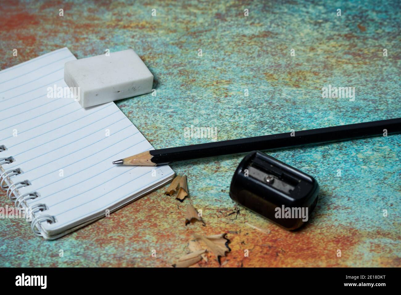 Notebook, black graphite pencil and eraser on a rustic metal surface ...