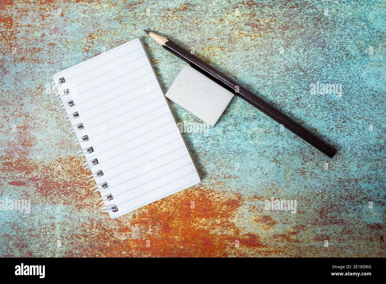 Notebook, black graphite pencil and eraser on a rustic metal surface ...