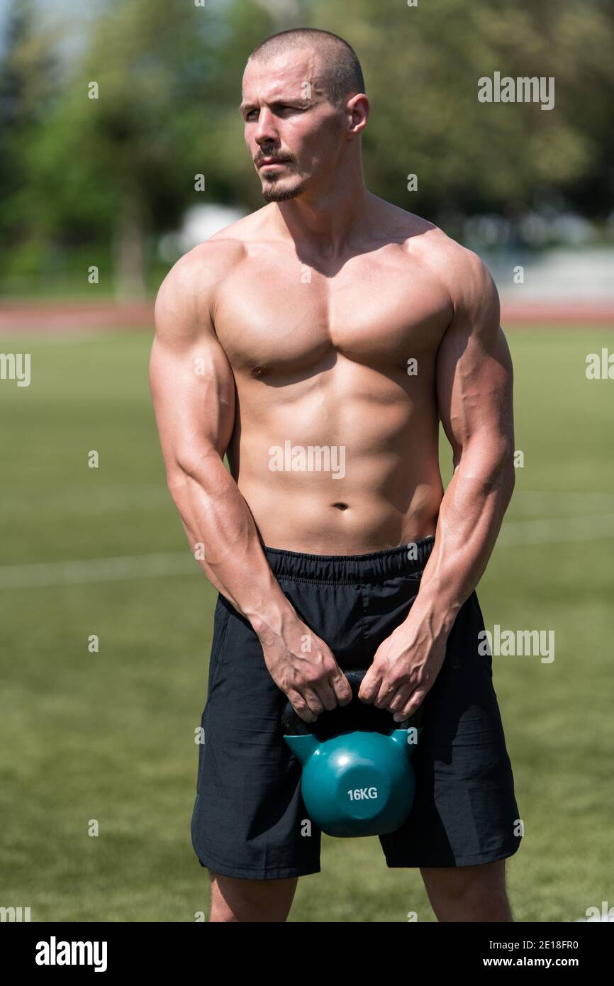 Man Exercising With Kettle Bell Outdoor and Flexing Muscles - Muscular ...