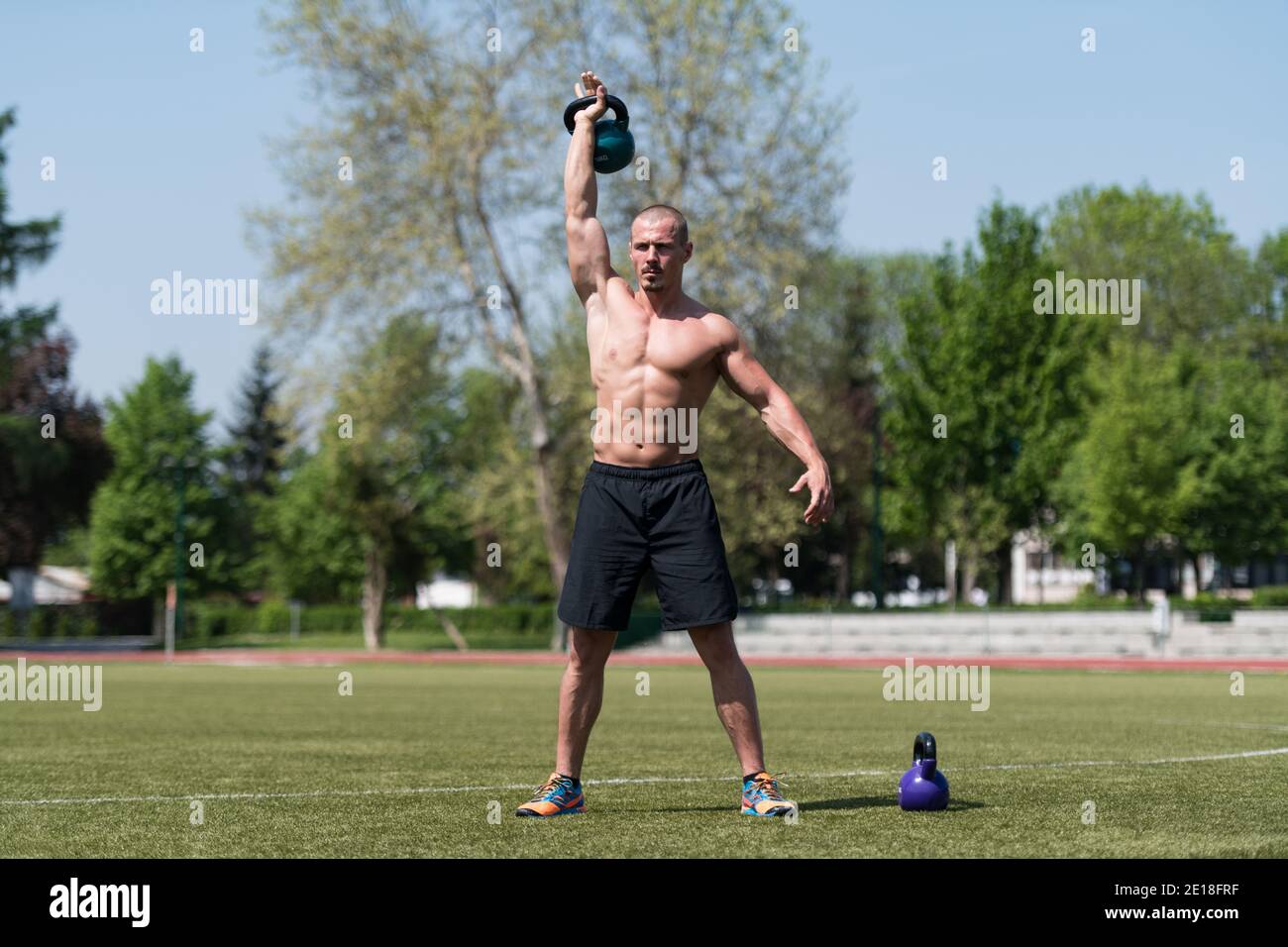 Man Exercising With Kettle Bell Outdoor and Flexing Muscles - Muscular ...