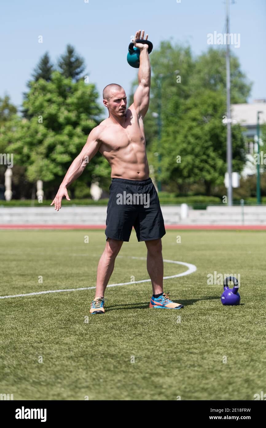 Man Exercising With Kettle Bell Outdoor and Flexing Muscles - Muscular ...