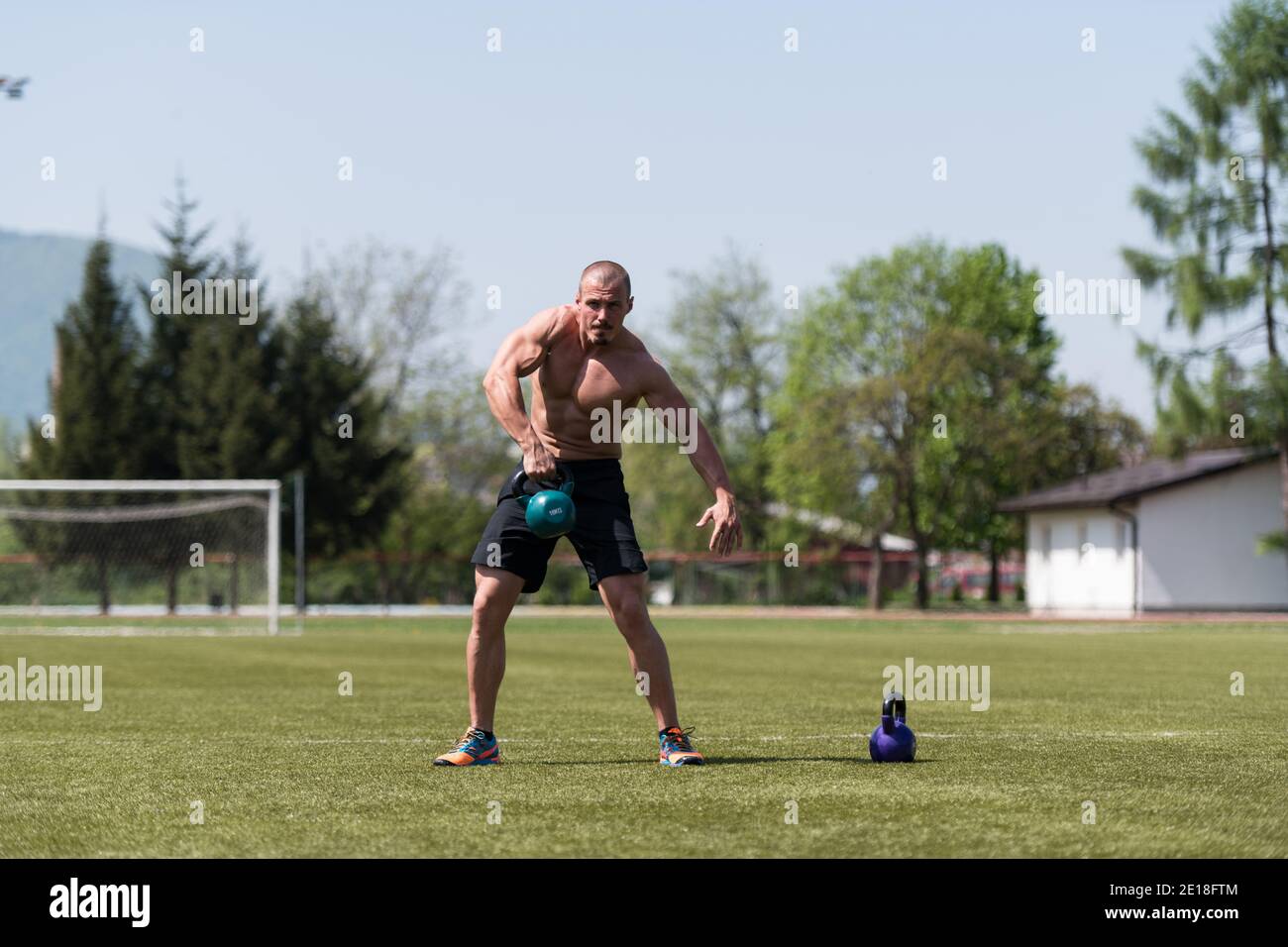 Man Exercising With Kettle Bell Outdoor and Flexing Muscles - Muscular ...