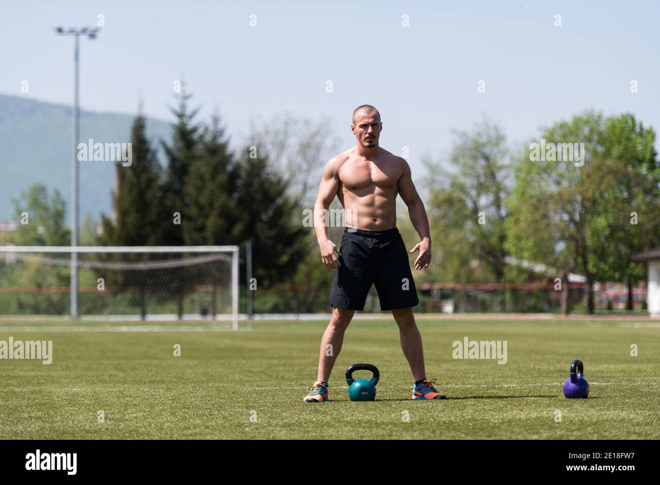 Man Exercising With Kettle Bell Outdoor and Flexing Muscles - Muscular ...