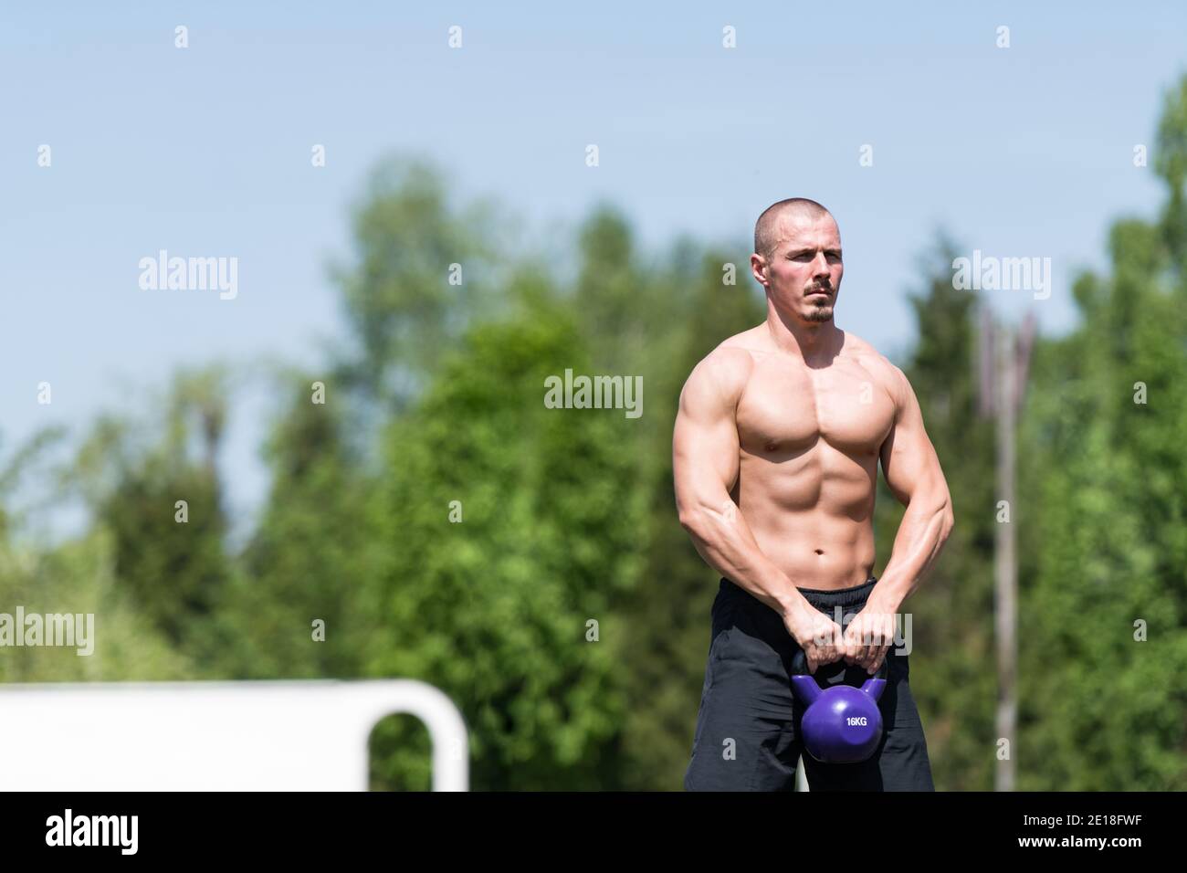 Man Exercising With Kettle Bell Outdoor and Flexing Muscles - Muscular ...