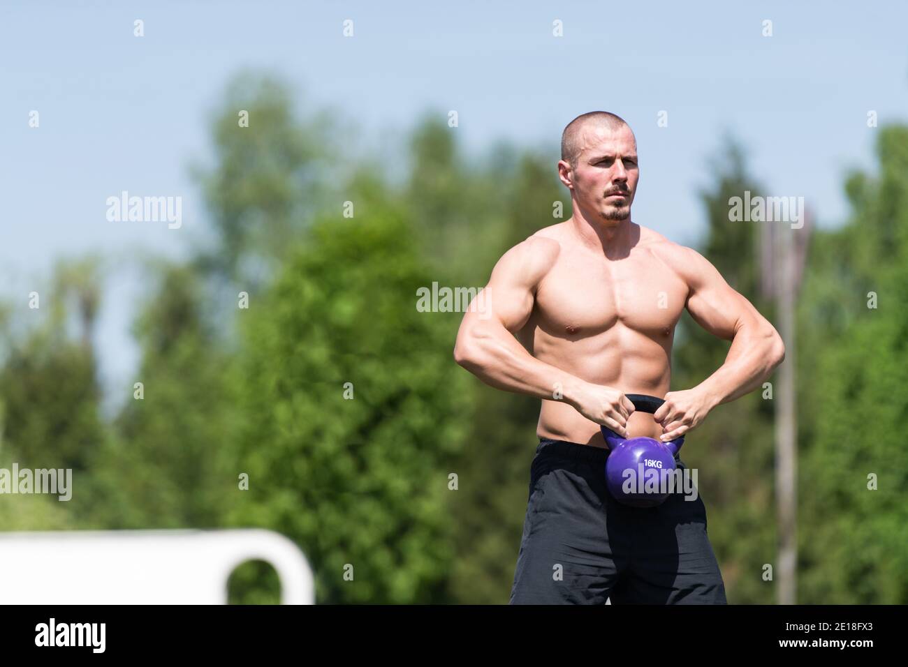 Man Exercising With Kettle Bell Outdoor and Flexing Muscles - Muscular ...