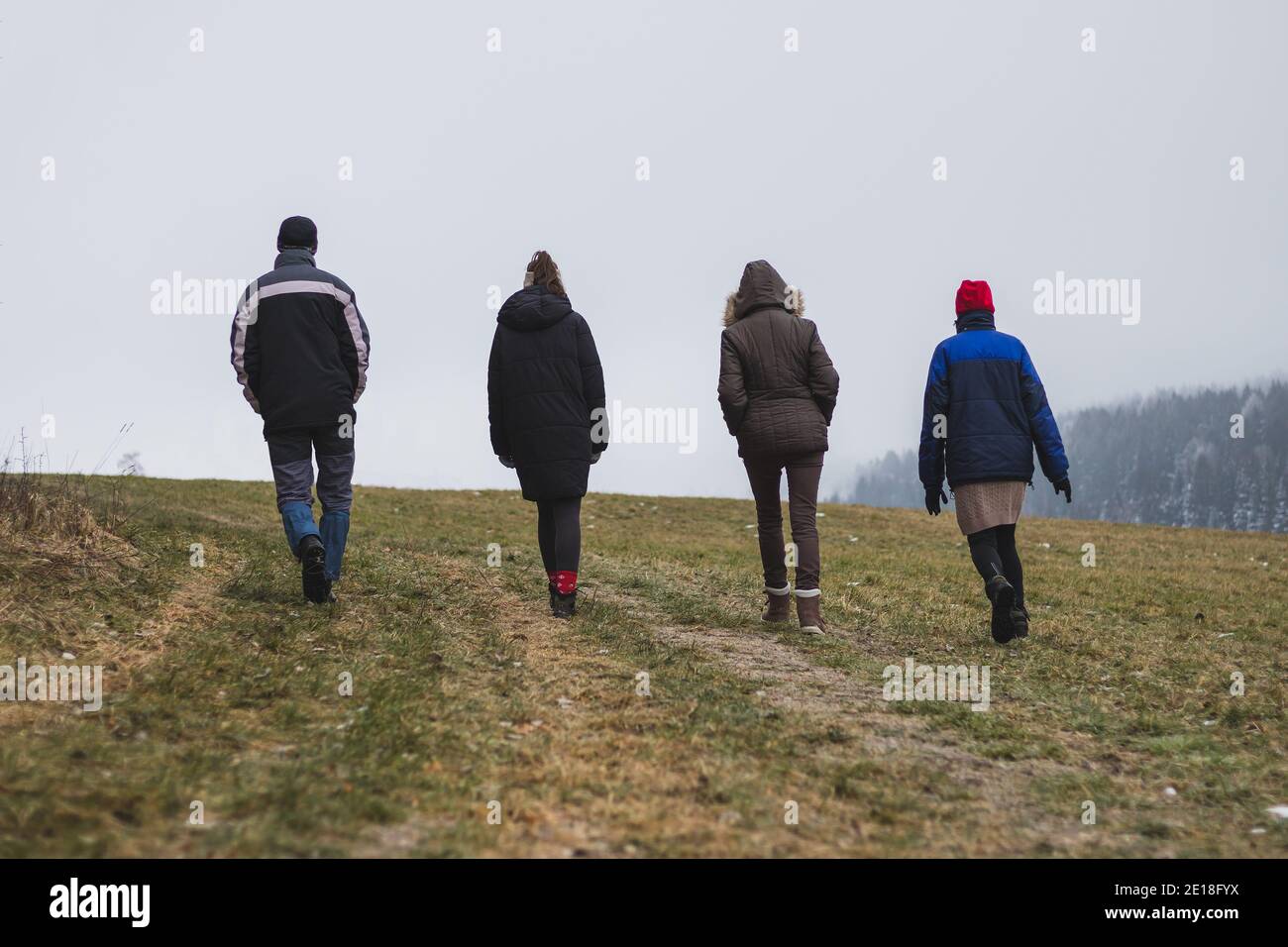 A group of people walk side by side through the countryside in cold ...