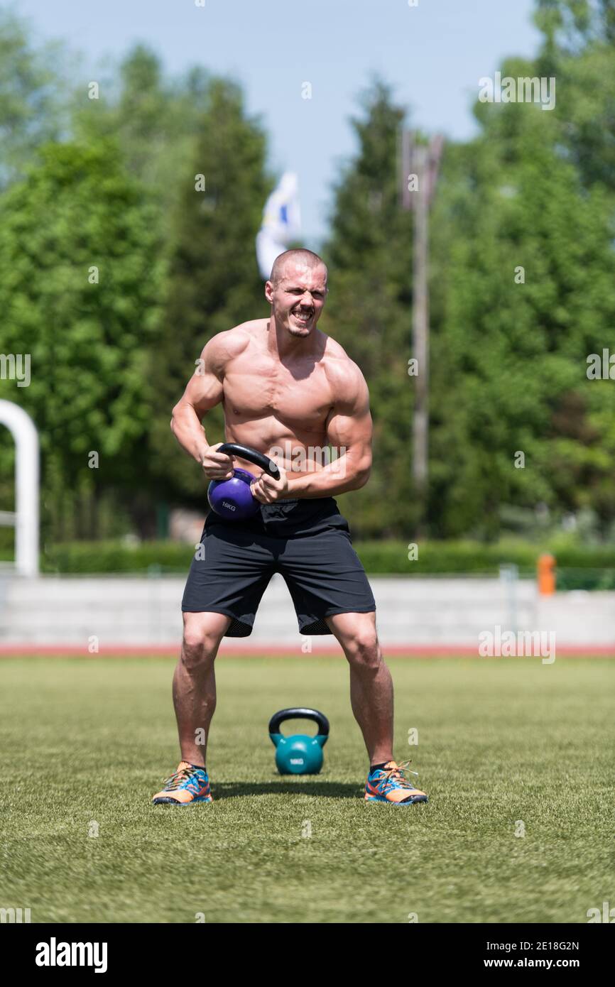 Man Exercising With Kettle Bell Outdoor and Flexing Muscles - Muscular ...