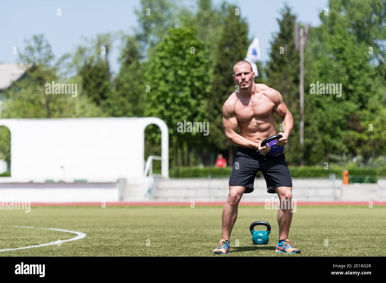 Man Exercising With Kettle Bell Outdoor and Flexing Muscles - Muscular ...