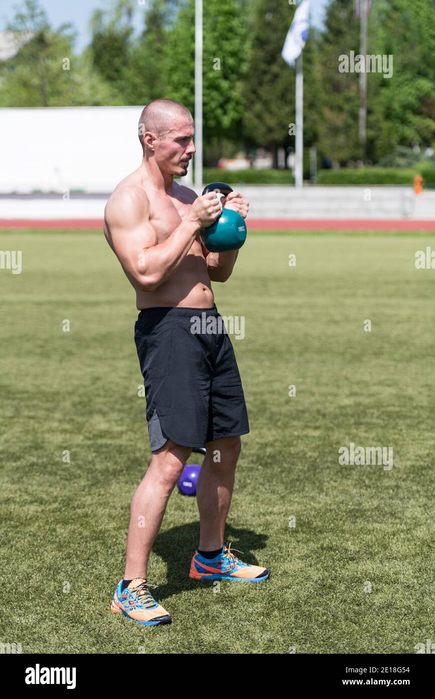 Man Exercising With Kettle Bell Outdoor and Flexing Muscles - Muscular ...