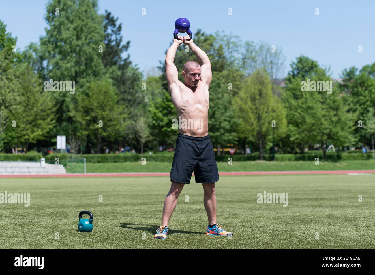 Man Exercising With Kettle Bell Outdoor and Flexing Muscles - Muscular ...