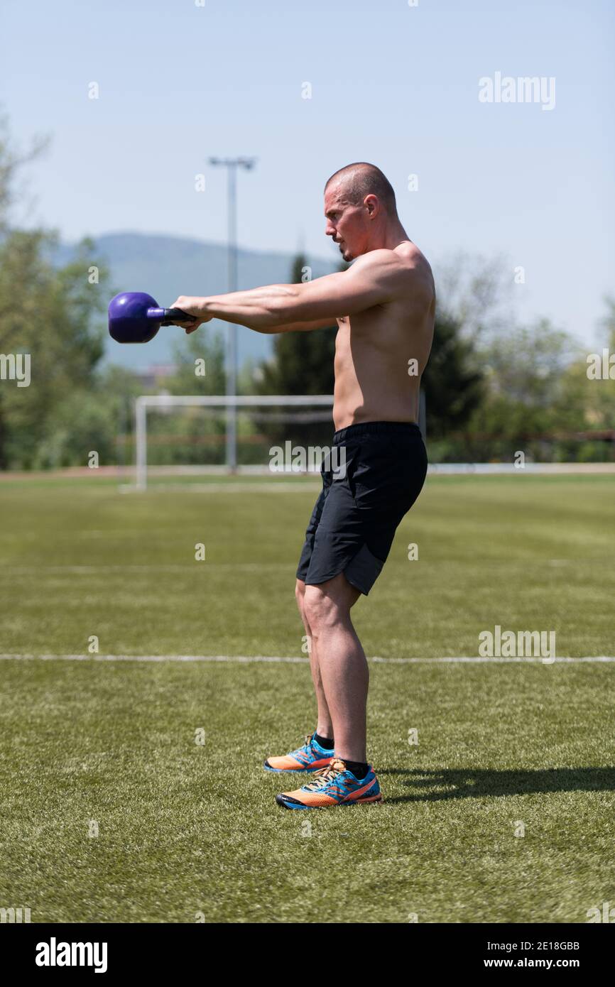 Man Exercising With Kettle Bell Outdoor and Flexing Muscles - Muscular ...