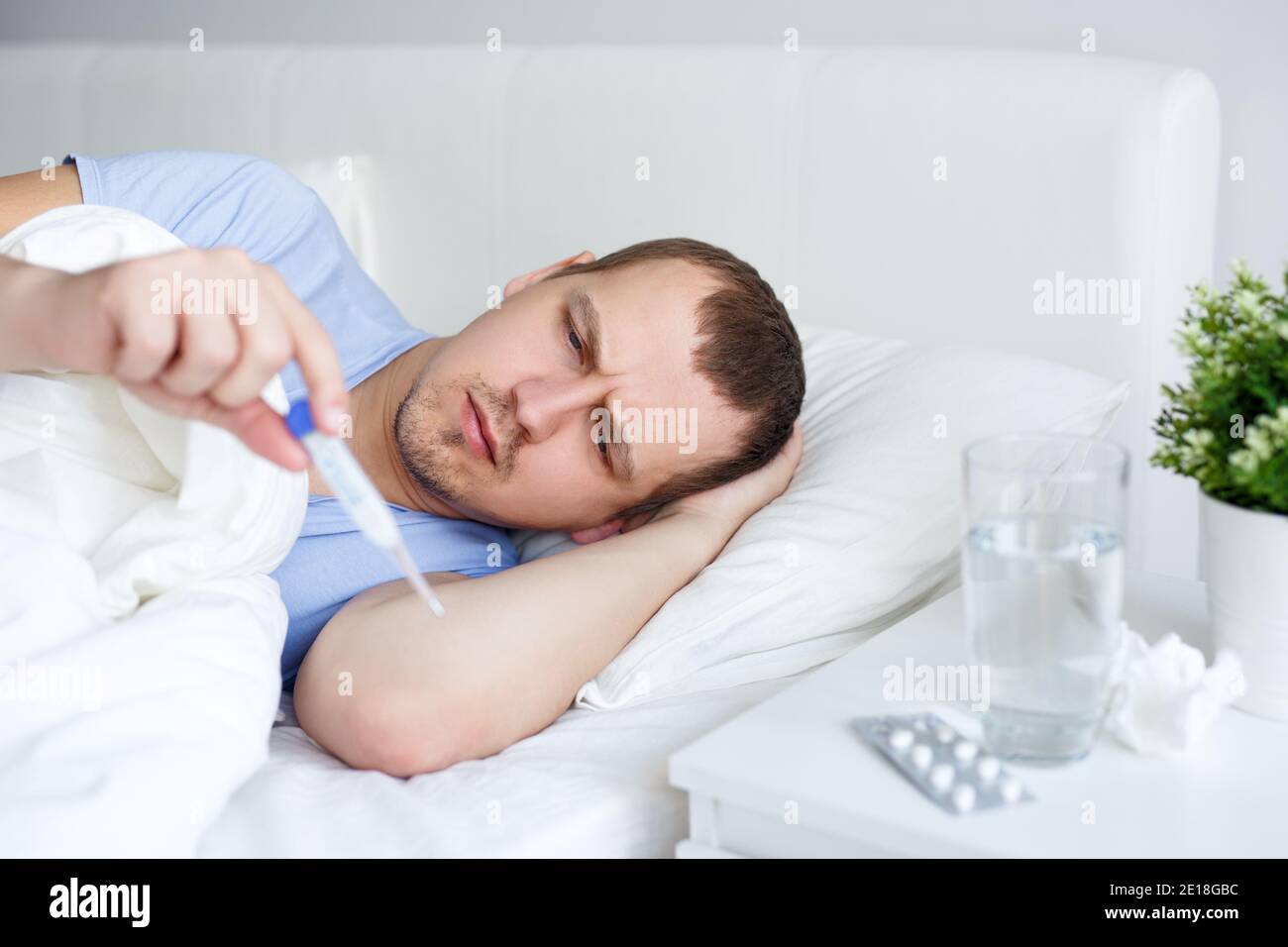 health care and illness concept - portrait of sick man with fever lying ...