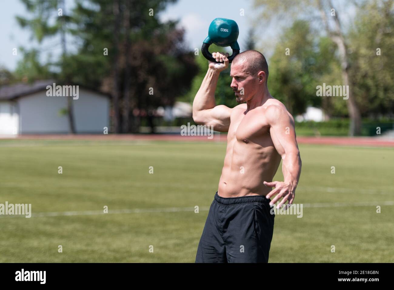 Man Exercising With Kettle Bell Outdoor and Flexing Muscles - Muscular ...
