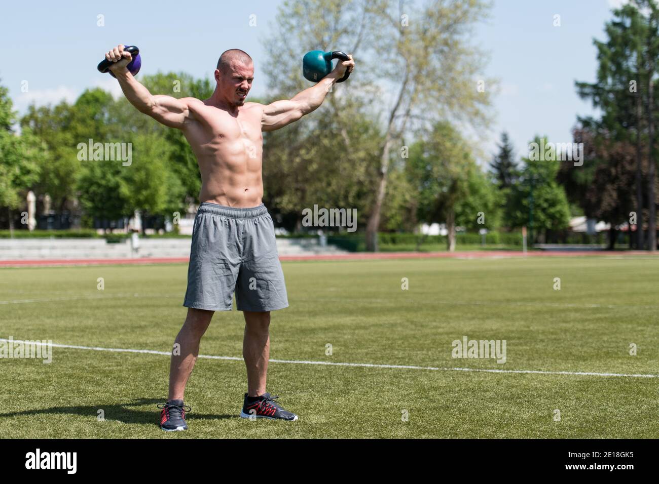 Man Exercising With Kettle Bell Outdoor and Flexing Muscles - Muscular ...