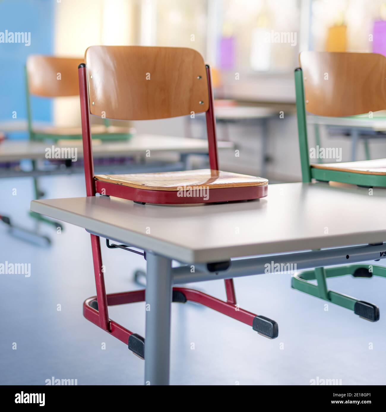 Red chair in a classroom stands on a table against a blurred background ...