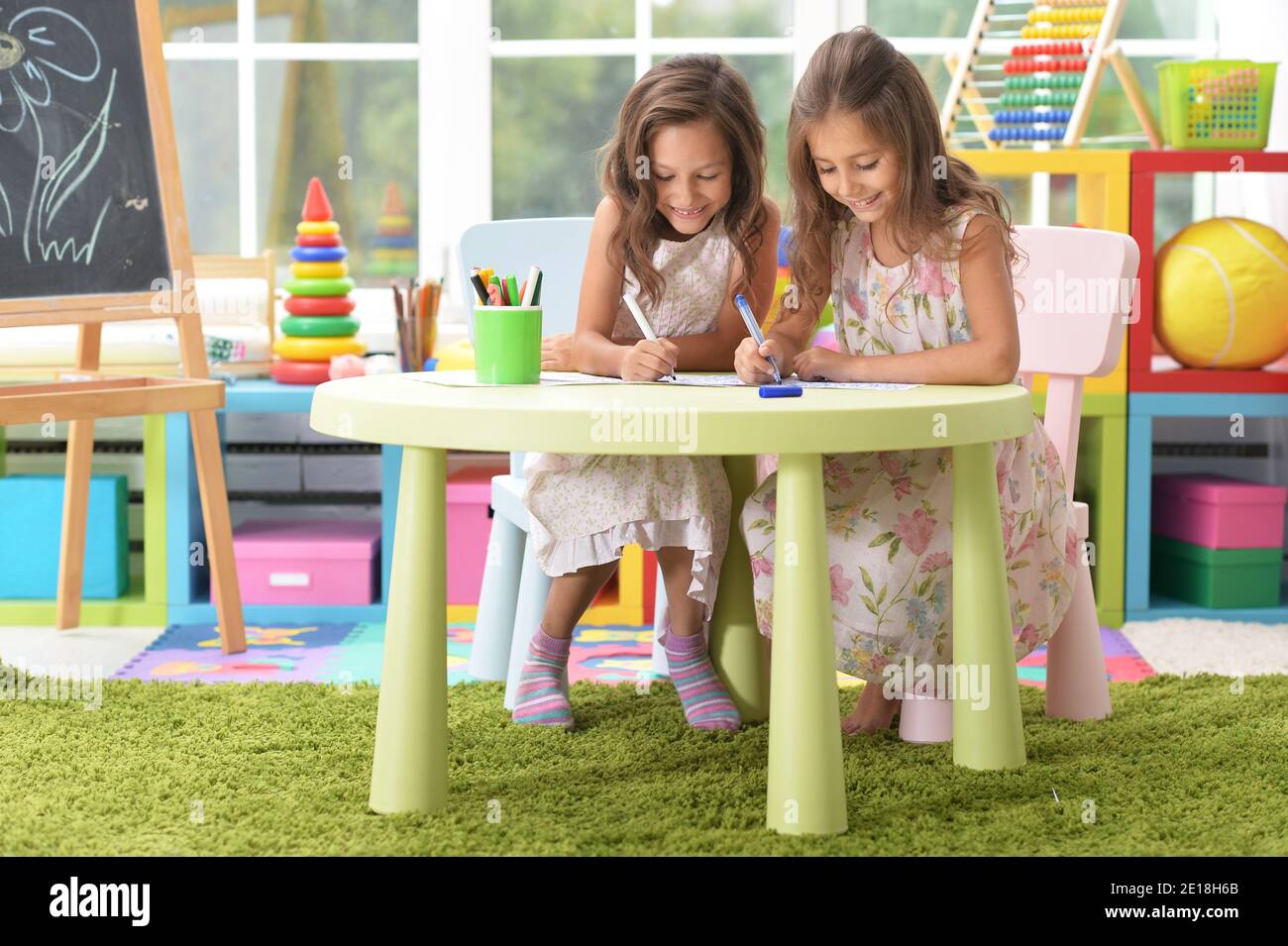Two cute little girls drawing with pencils Stock Photo - Alamy