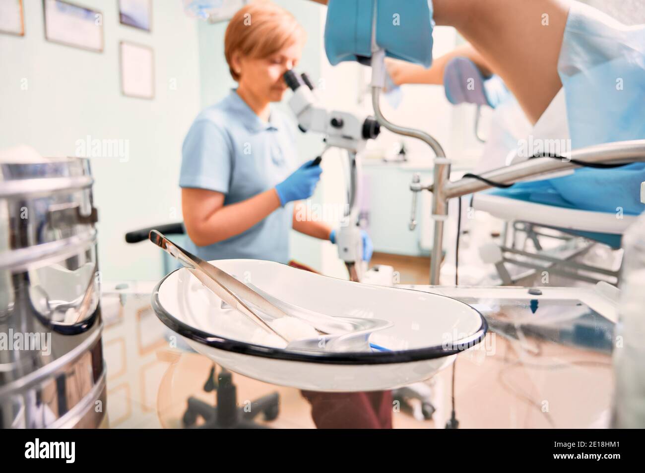 Gynecological instruments on foreground. Doctor examining woman with ...