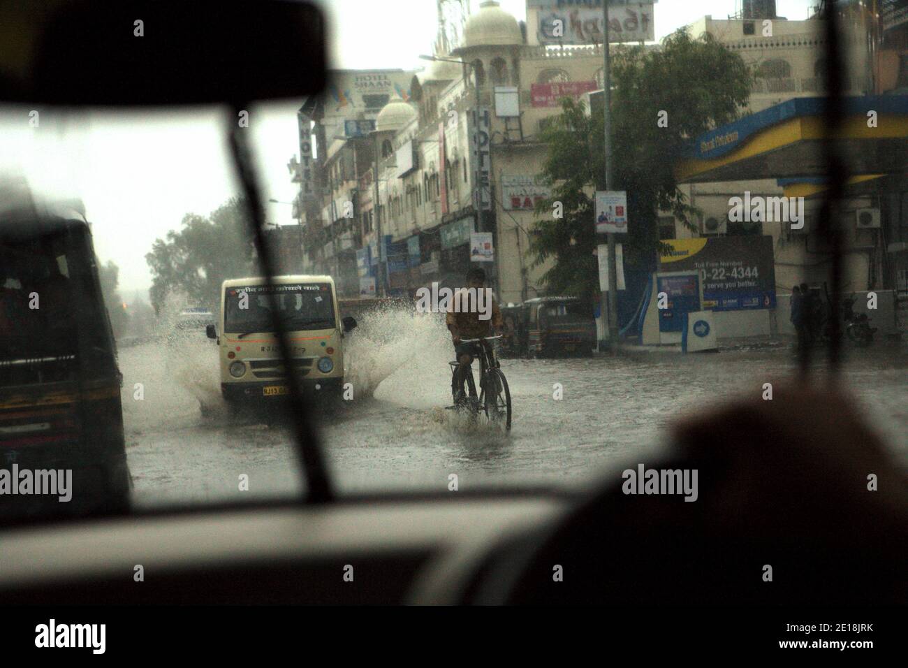 Vehicles negotiating with a road flooded with rainwater during a heavy ...