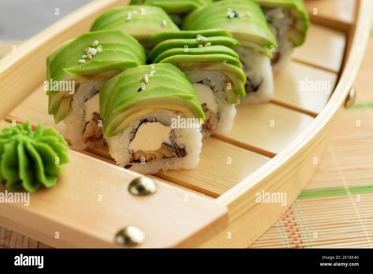 Dragon sushi roll covered with avocado pieces Stock Photo - Alamy