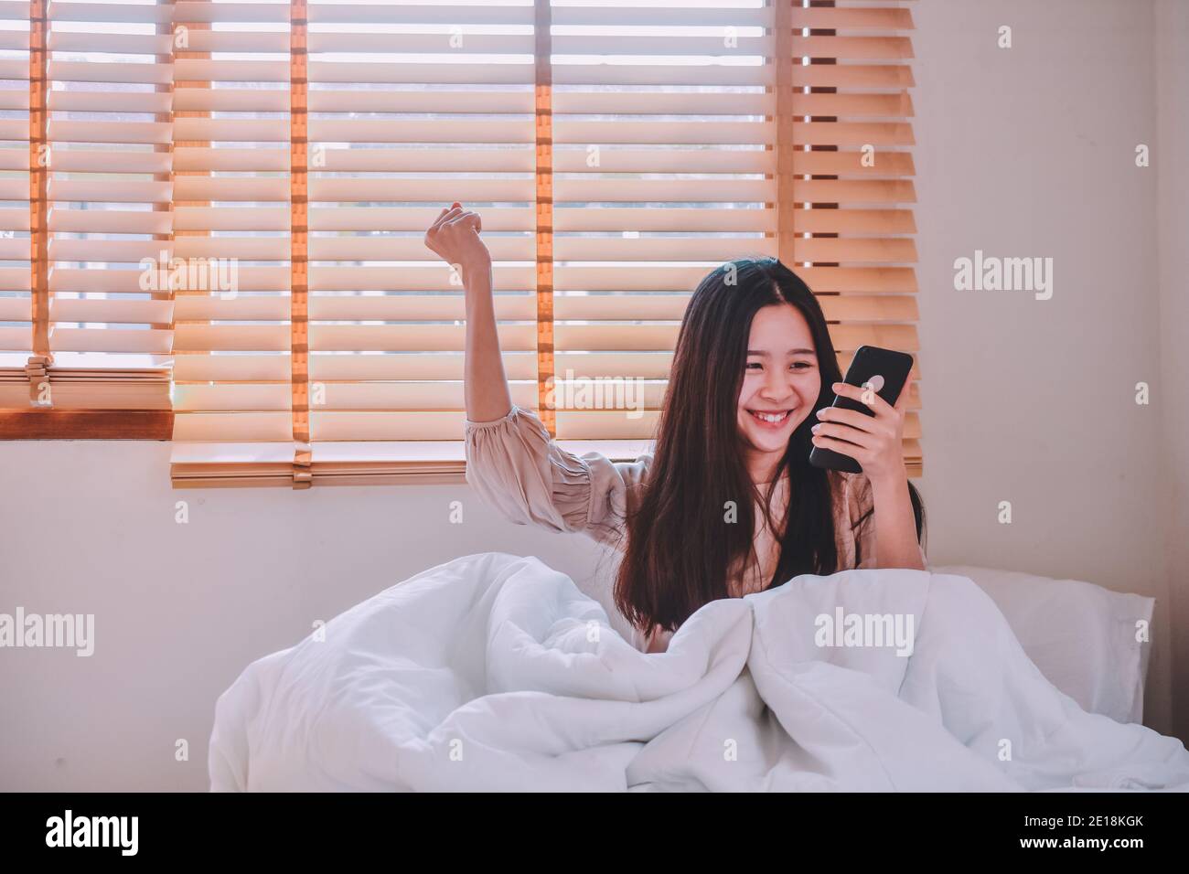 Women holding Mobile smartphone sitting on bed in room Stock Photo - Alamy