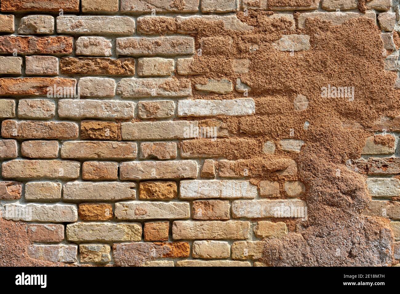Background from a red rough brick wall with the remains of some plaster ...