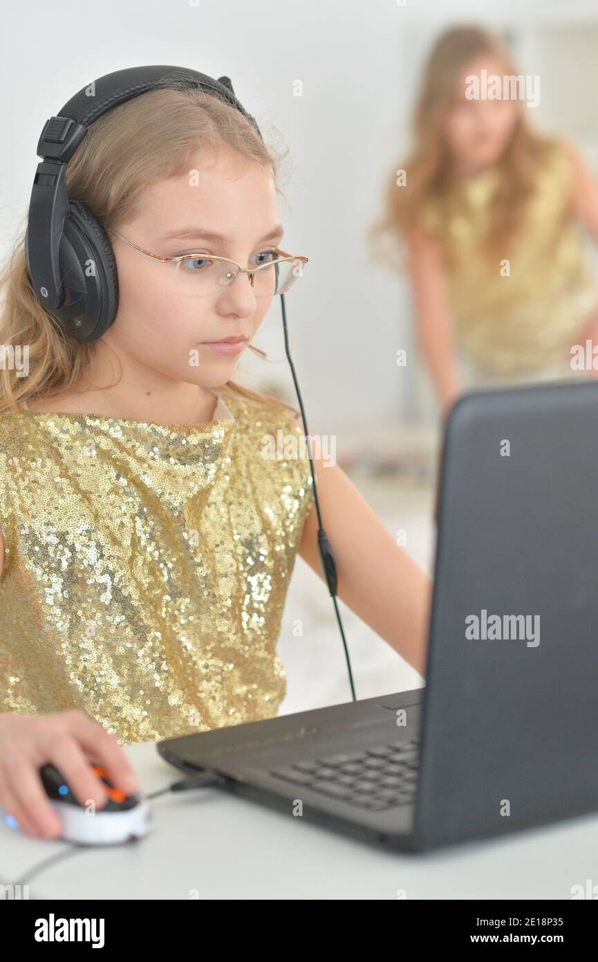 Focused teen girl in headphones using laptop at home. Computer ...