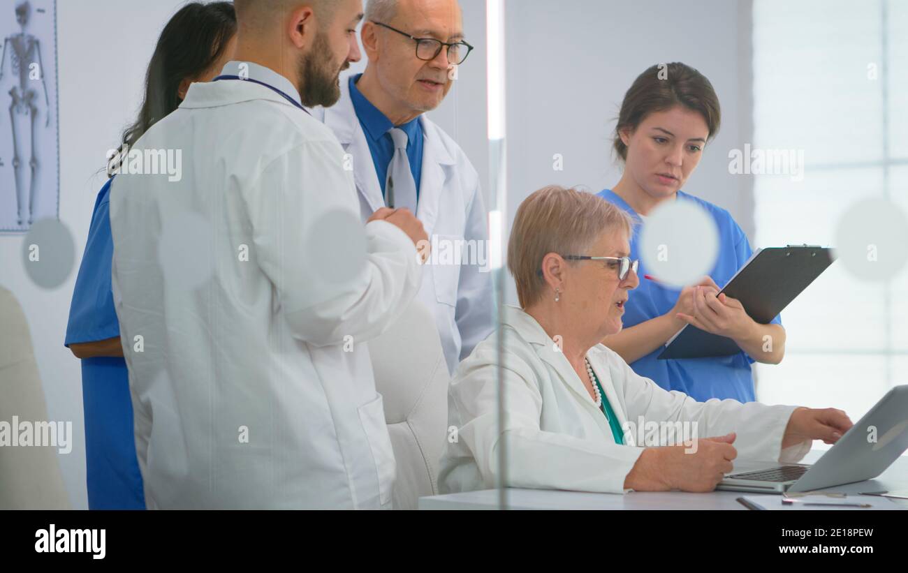 Team of doctors standing in conference hospital room, senior doctor ...