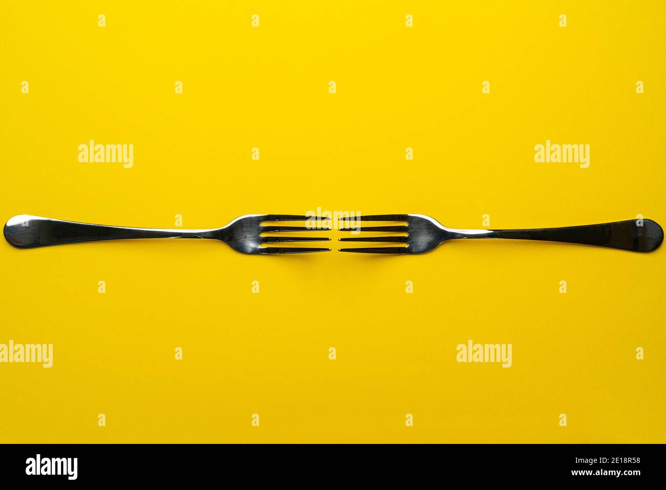 two forks arranged on a yellow surface Stock Photo - Alamy