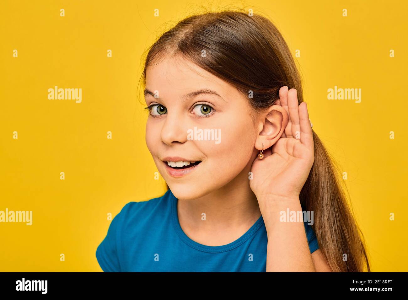 Hearing test concept. Positive girl holds hand near the ear, isolated ...