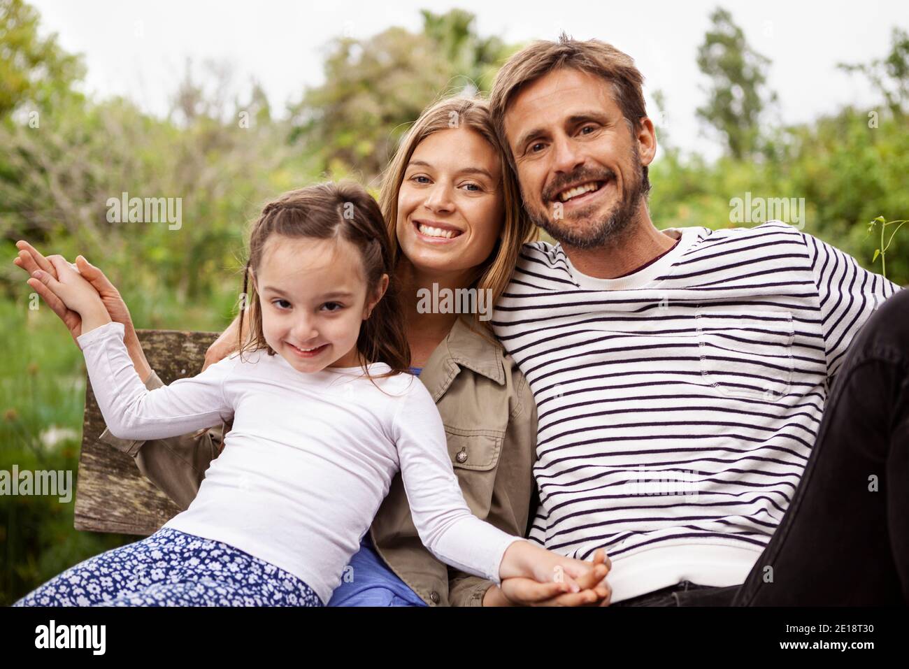 Portrait of happy family sitting on bench Stock Photo - Alamy
