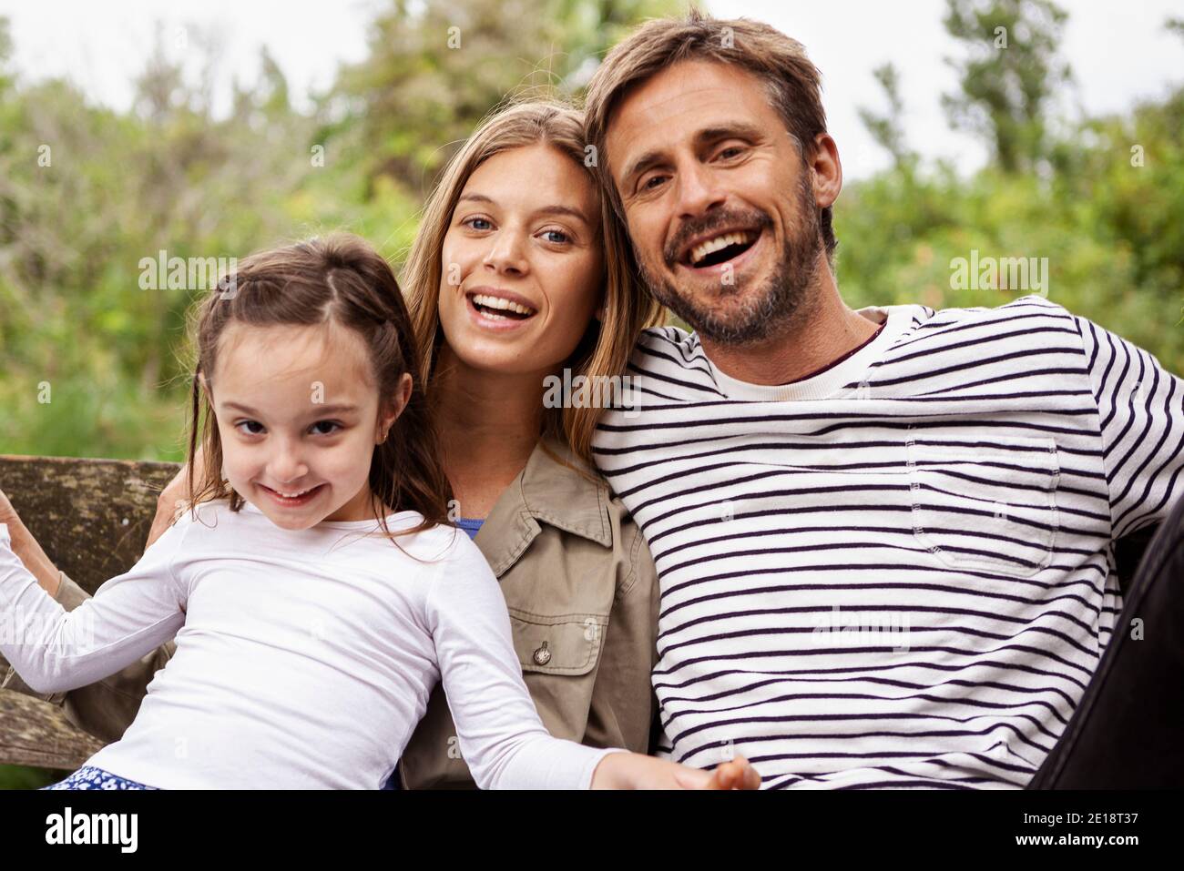 Portrait of happy family sitting on bench Stock Photo - Alamy