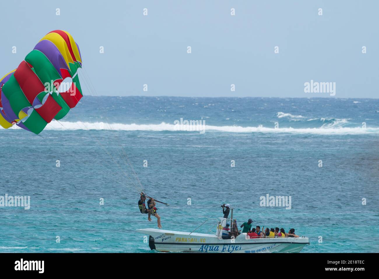 parasailing boat and tandem couple on open parachute getting ready to ...