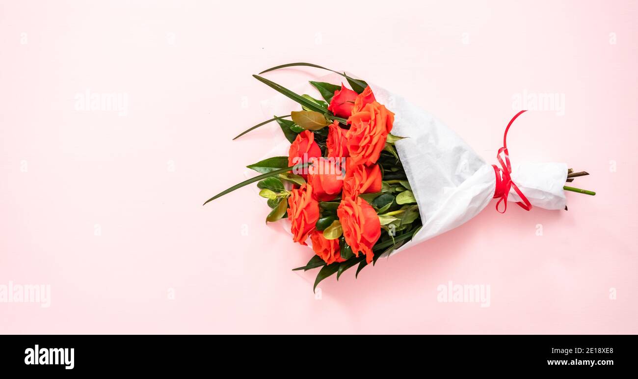 Flat lay. Bouquet of red roses and green leaves on a pink background ...