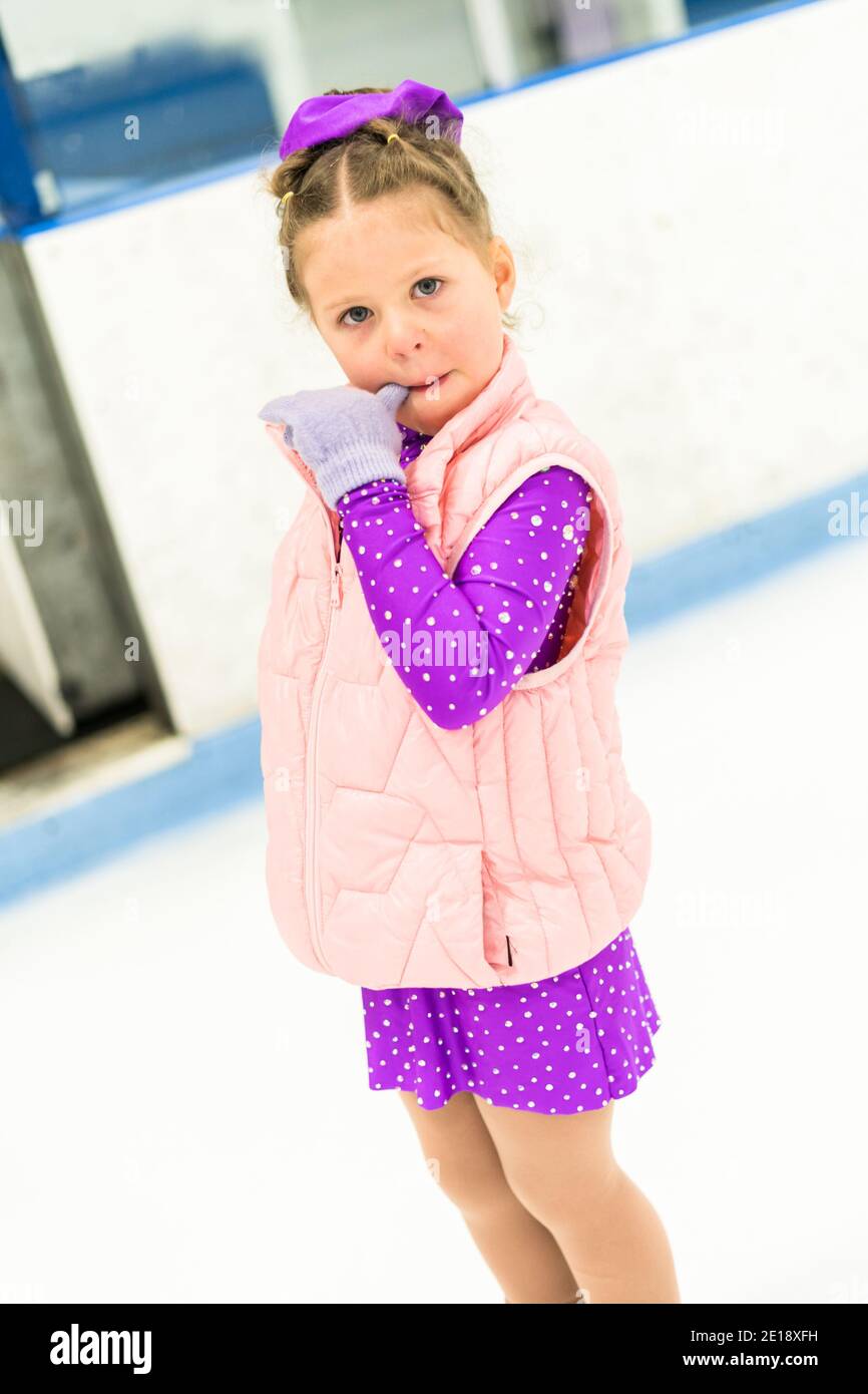 Little girl practicing figure skating in a purple dress with crystals ...