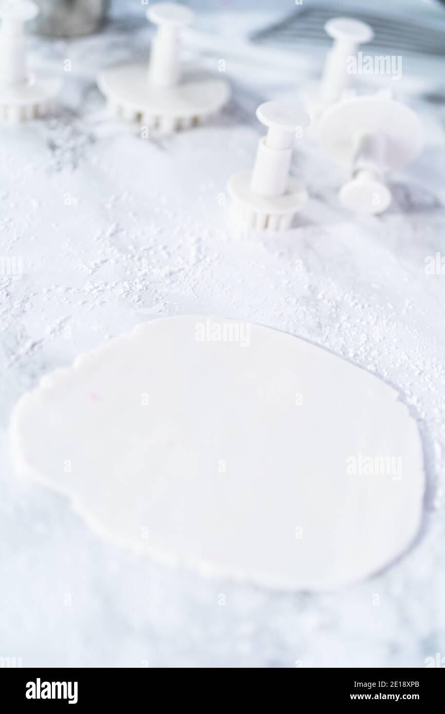 Rolling out fondant to cut snowflake shapes with cookie cutters Stock ...
