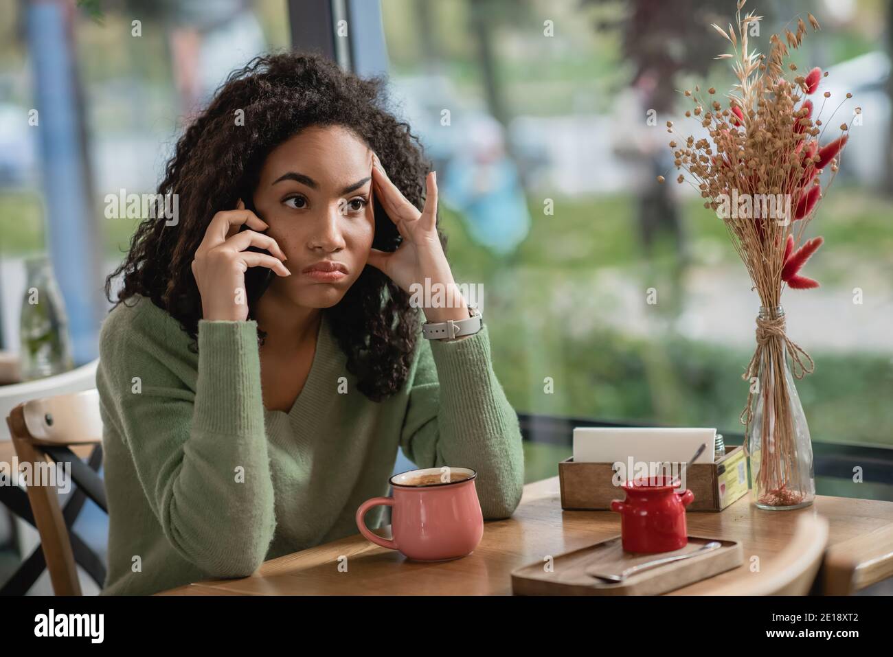 sad african american woman puffing cheeks while talking on phone in ...